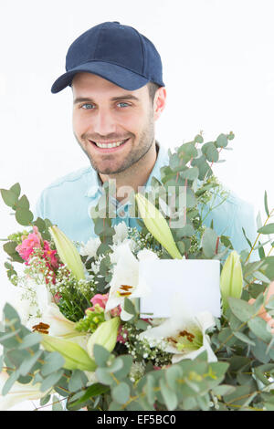 Happy young delivery man with bouquet of beautiful tulips on grey ...