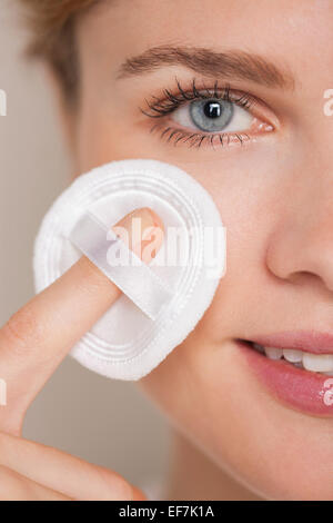 Young woman applying a powder foundation with brush on her face Stock ...