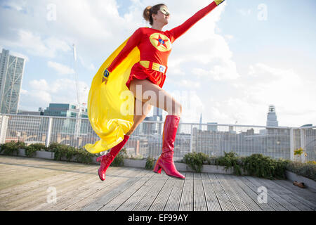 Superhero jumping on city rooftop Stock Photo - Alamy
