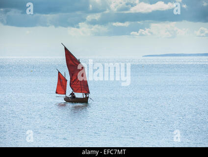 Sailing boat with red sails at Beer Devon England Stock Photo - Alamy
