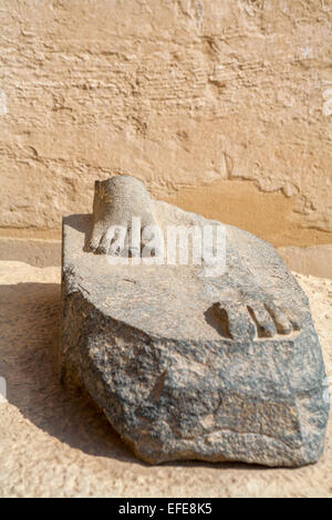 Close up of the sandstone plinth of a statue showing two bare feet ...