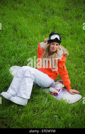 girl with a snowboard is sitting on the grass Stock Photo - Alamy