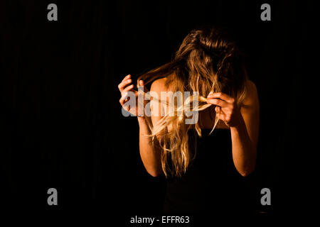 Woman disentangling her hair in front of black background Stock Photo ...