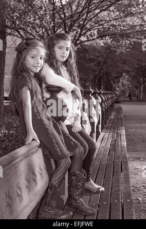 Two girls sitting on bench in park and laughing Stock Photo - Alamy