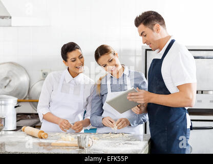 Chefs Checking Recipe On Tablet Computer In Kitchen Stock Photo - Alamy
