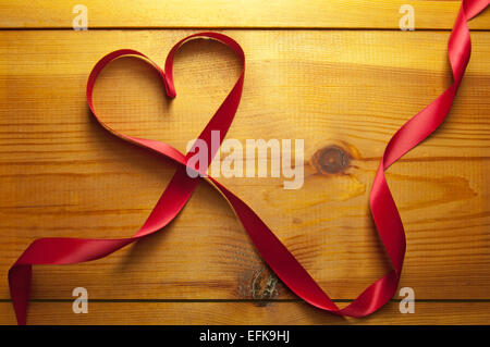 Heart made of red satin ribbon on table against blurred lights Stock ...