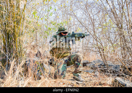 Camouflage Hunter or soldier hiding in bushes in camouflage autumn ...