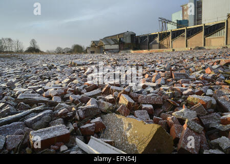 piles of rubble on derelict land and factory building covered by winter ...