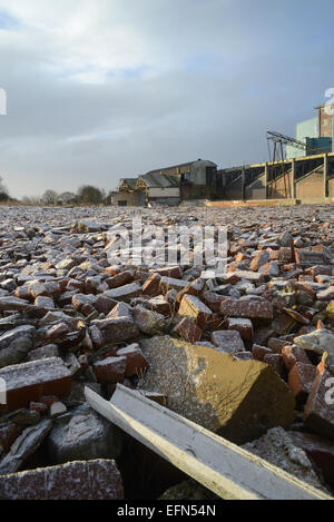 piles of rubble on derelict land and factory building covered by winter ...