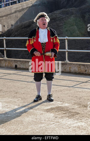 Male town crier (colourful red braided crier's livery) proclaiming ...