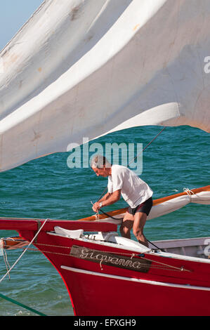Lateen (Latin) sail boat and crew on the sea near the coast of Palau ...