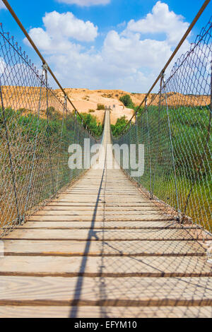 Bridge over a river in a desert. The bridge is wooden and spans the ...