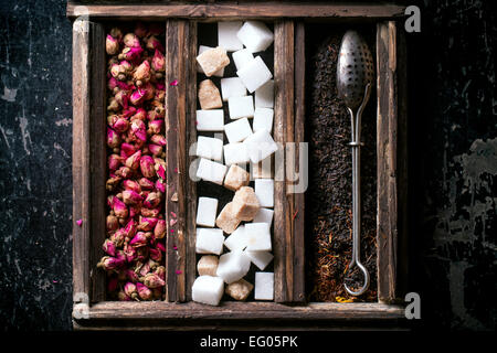 dry black tea in a wooden spoon on a white plate with raspberries and ...