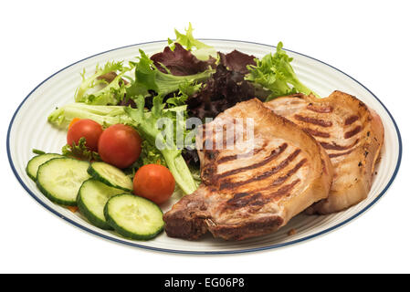 Juicy grilled pork chop with char marks on white plate. Rustic wooden ...