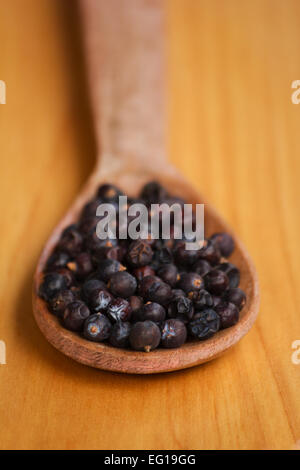 Wooden spoon with seeds of juniper on an old dark blue table Stock ...