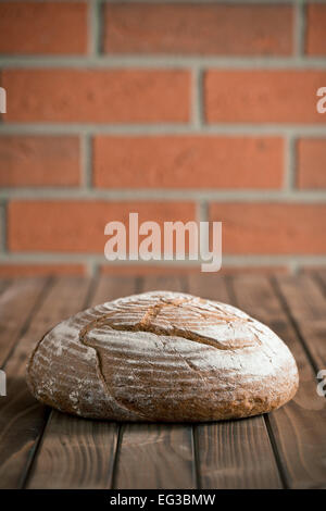 Round baked bread on a wooden board, brown table. View from above Stock Photo - Alamy