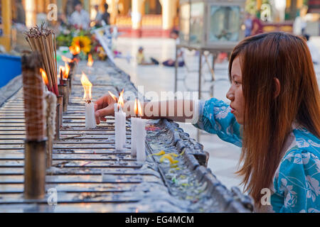 Burmese girl burning incense sticks / joss sticks in the Shwedagon Zedi ...