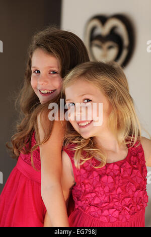 Happy sisters in pink dresses smiling and standing together Stock Photo ...