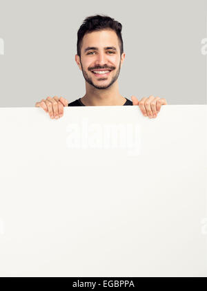 Young handsome man holding advertising banner over yellow isolated ...