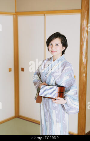 Woman in yukata holding a tub and hand towel at a hot spring ryokan in ...