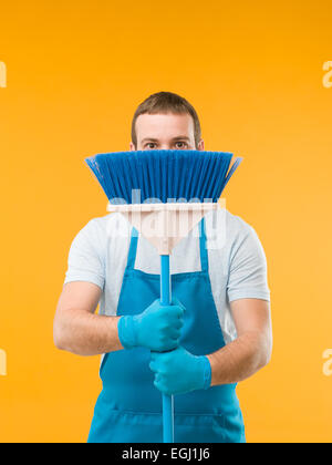 Young cleaner man with blue eyes cleaning wearing apron and gloves ...