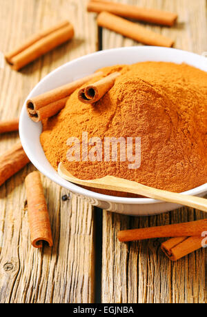 Bowl of cinnamon powder and sticks on color background Stock Photo - Alamy