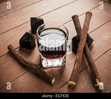 Licorice liqueur with pure blocks and roots on wooden table Stock Photo ...