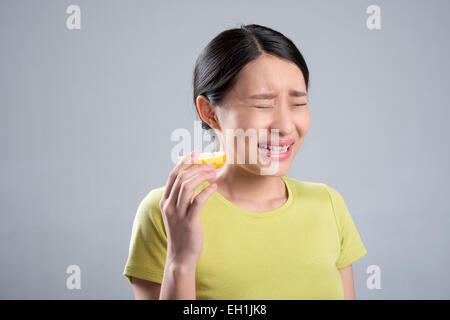 Young beautiful woman eating a lemon over yellow isolated background ...