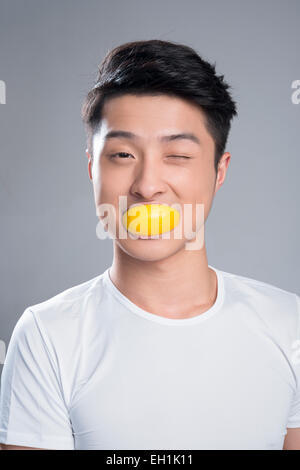 Young man has a sour emotion while tasting a lemon Stock Photo - Alamy