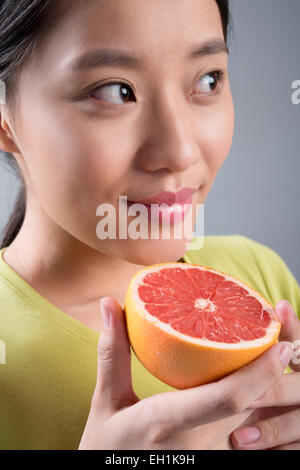 Beautiful young Asian woman with grapefruit on color background Stock ...