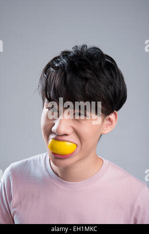 Young man has a sour emotion while tasting a lemon Stock Photo - Alamy