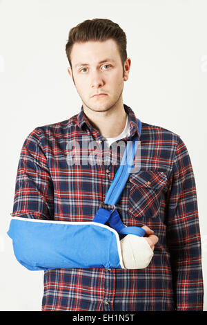 Young man with broken arm in sling smiles, raising thumb near empty ...