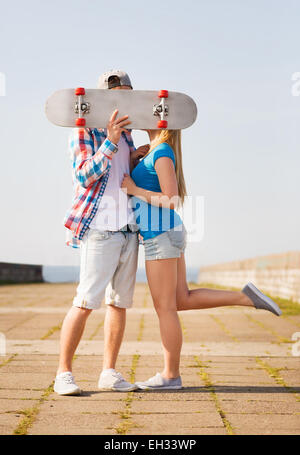 Happy young couple with skateboard hugging on lilac background Stock ...
