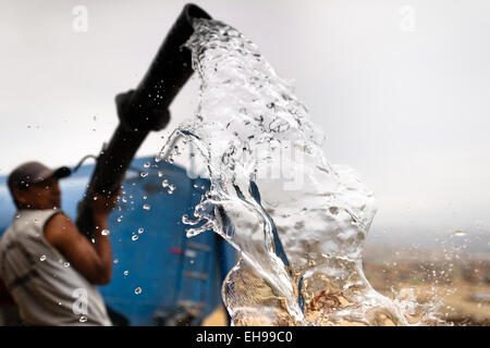 A Peruvian water distribution worker with a pipe splashes drinking ...