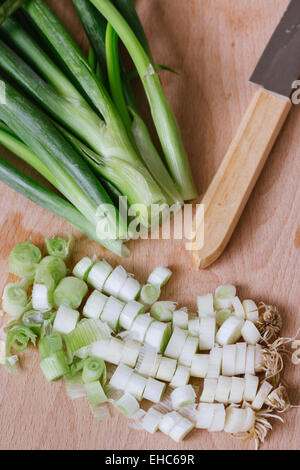 Fresh green onions on a cutting board over white wooden background ...