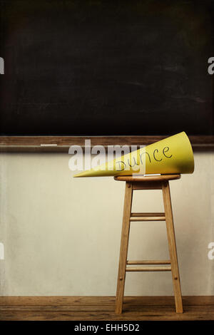 Yellow dunce hat on stool with chalkboard in background Stock Photo - Alamy
