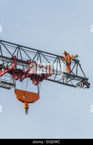 A construction worker on the jib or working arm of a crane on a ...