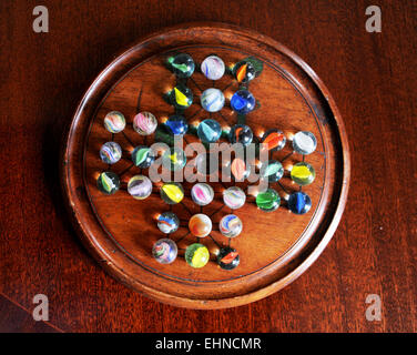Old fashioned traditional solitaire game with wooden board and glass ...
