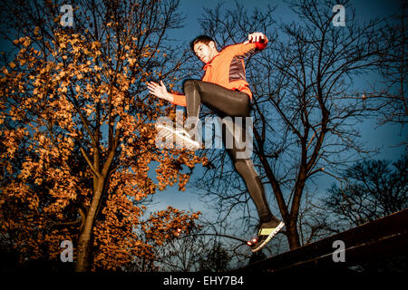 Male runner jumping over bench in park Stock Photo - Alamy