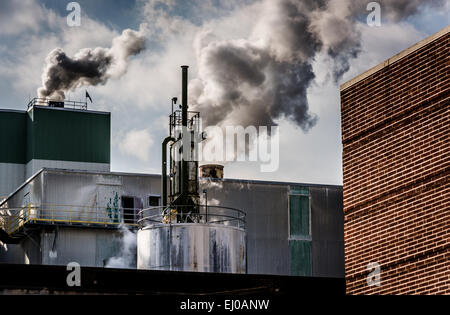 Industry. A paper mill building with steam or smoke plumes against a ...