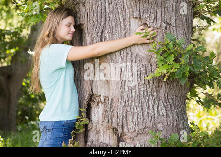 pretty blonde woman hugging a tree branch in a white dress Stock Photo ...
