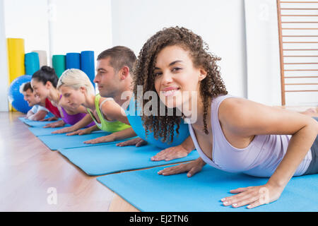 Woman practicing push-ups with fitness ball against gray background ...
