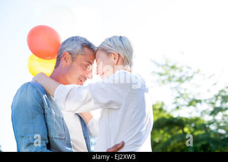 Cute couple hugging and holding balloons in the park Stock Photo - Alamy