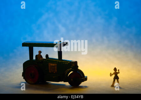 Miniature toy steamroller with mini figure of girl in studio setting ...
