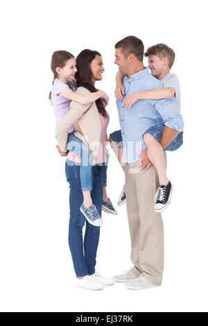Parents giving piggyback ride to children against trees Stock Photo - Alamy