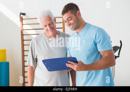 Senior man with coach looking at clipboard Stock Photo - Alamy