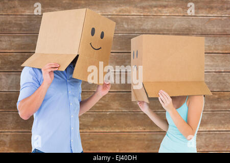 Composite image of couple wearing emoticon face boxes on their heads ...