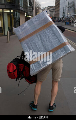 A man carrying a heavy and awkward load on his shoulders through the ...
