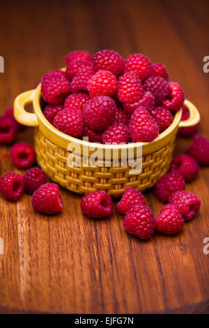 Bunch of raspberries in yellow ceramic bowl on a dark brown wood ...