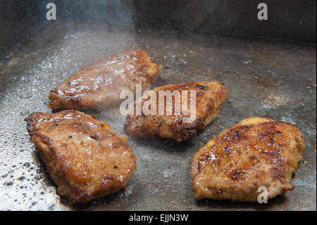 Closeup of chicken escalope panne cooking on grill hot plate at a hotel ...